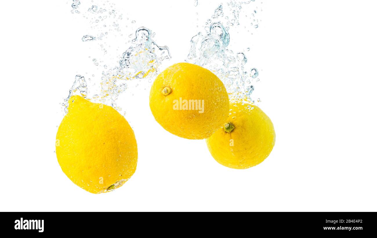 Lemons splash into water and sinking on white background Stock Photo - Alamy