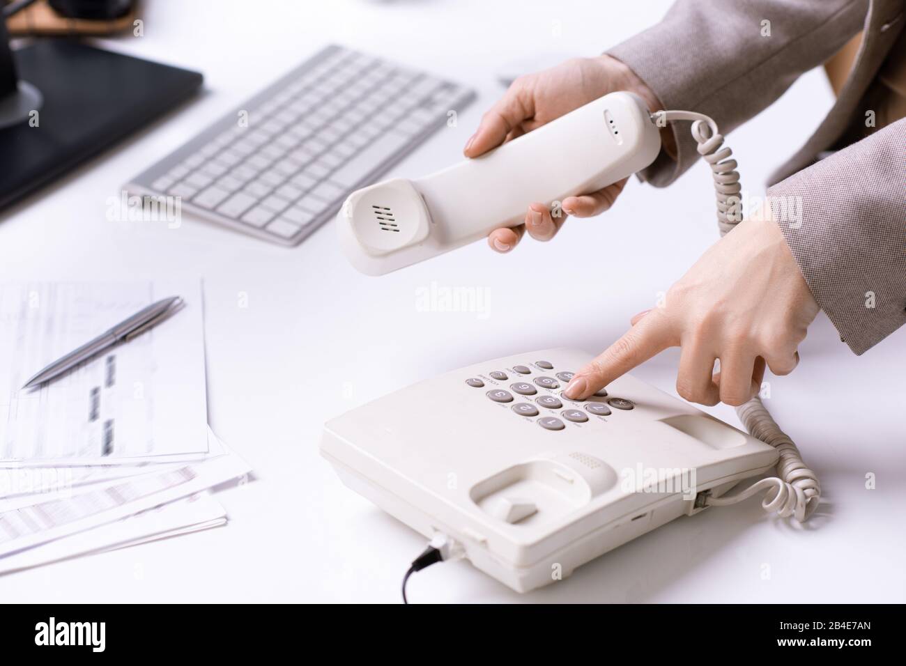 Hands of young office secretary dialing phone number and holding ...
