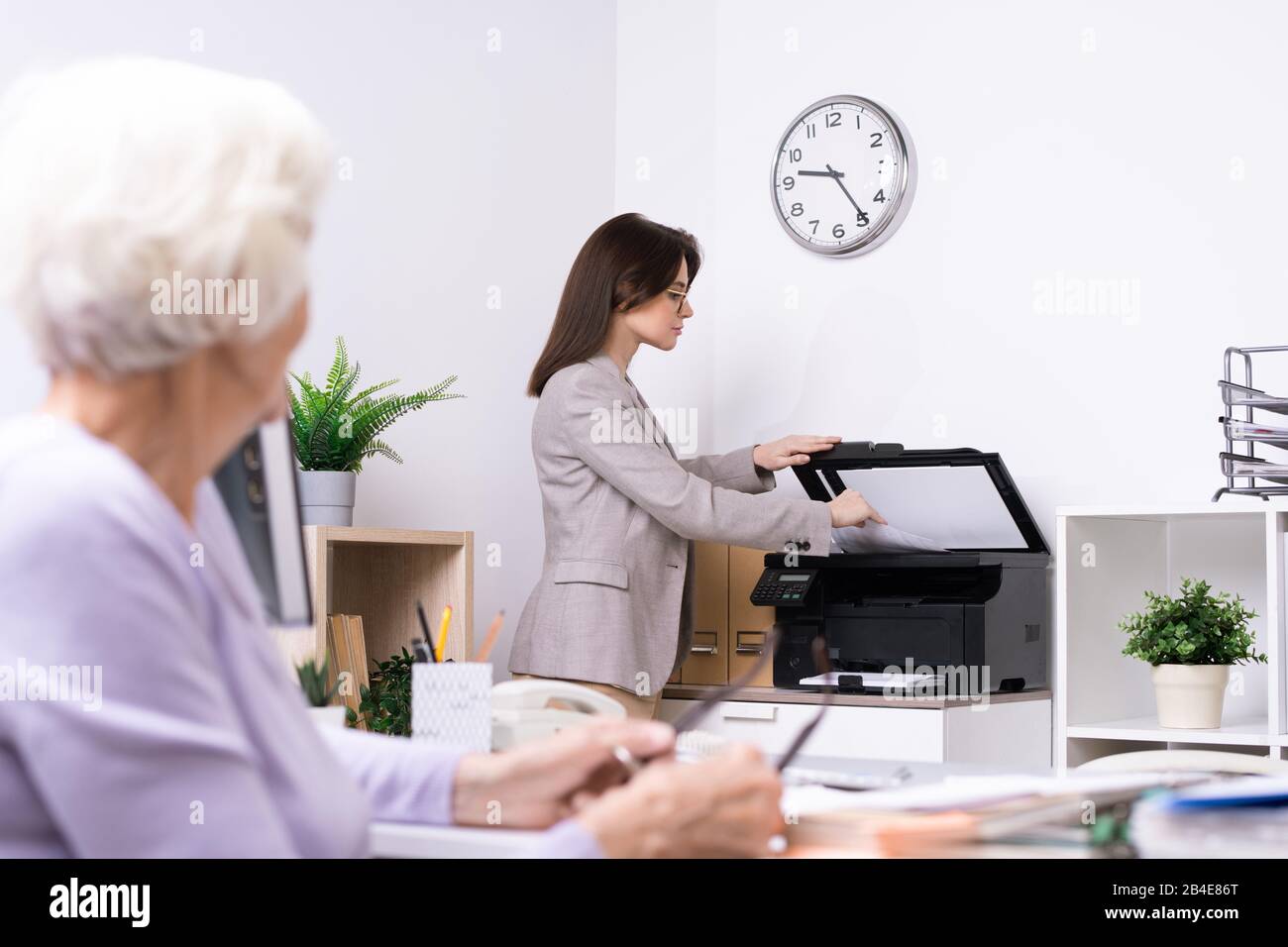 Young elegant office secretary or insurance agent making copy of ...