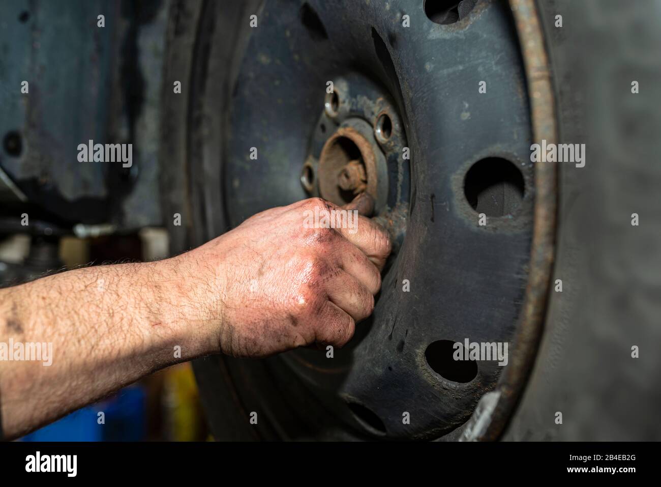 The car mechanic inserts the bolts securing the steel wheel of the car ...