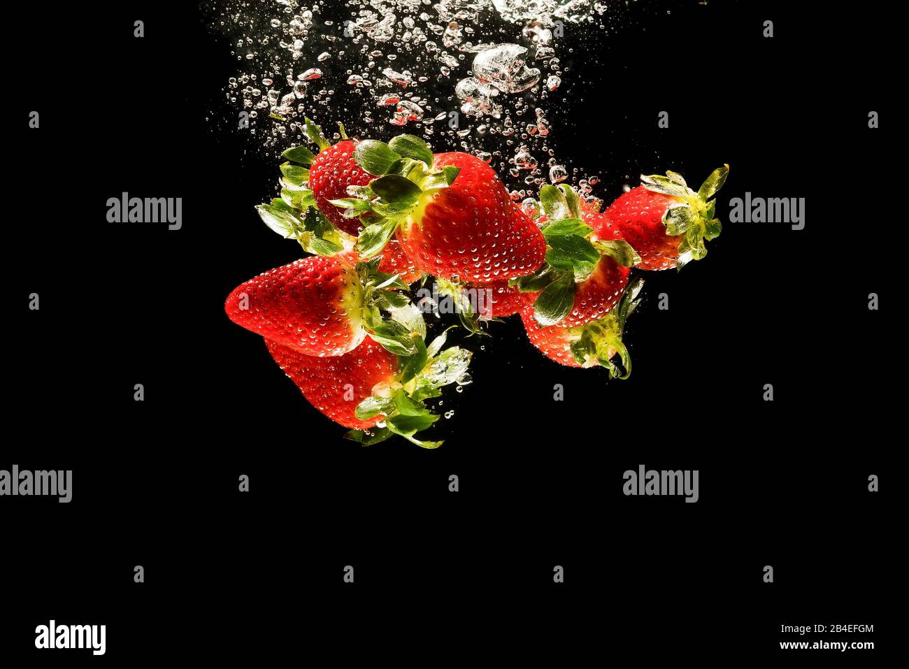 Strawberries falling into water causing bubbles all around it. Healthy ...