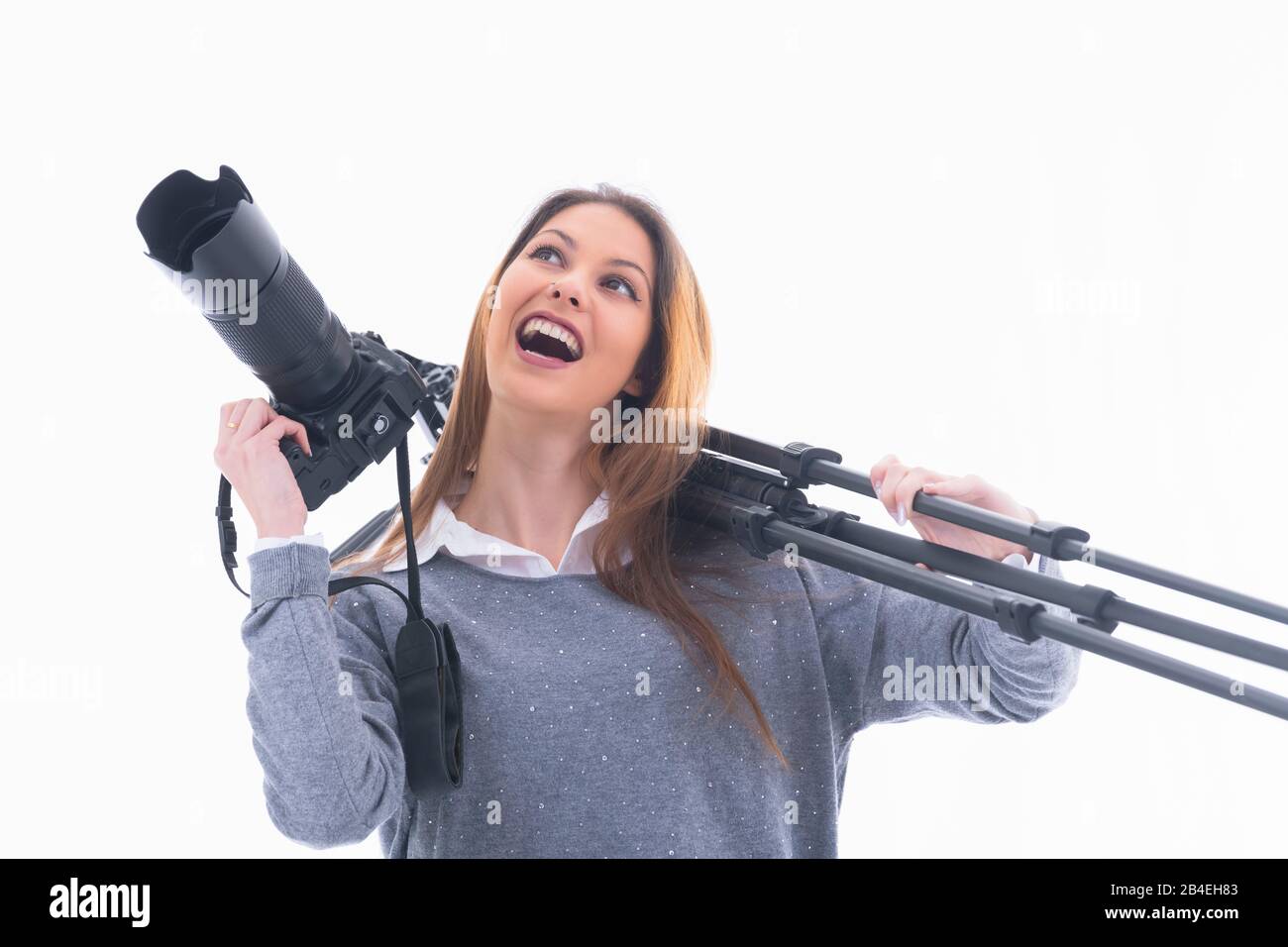 Woman holding a camera and carrying a tripod Stock Photo - Alamy