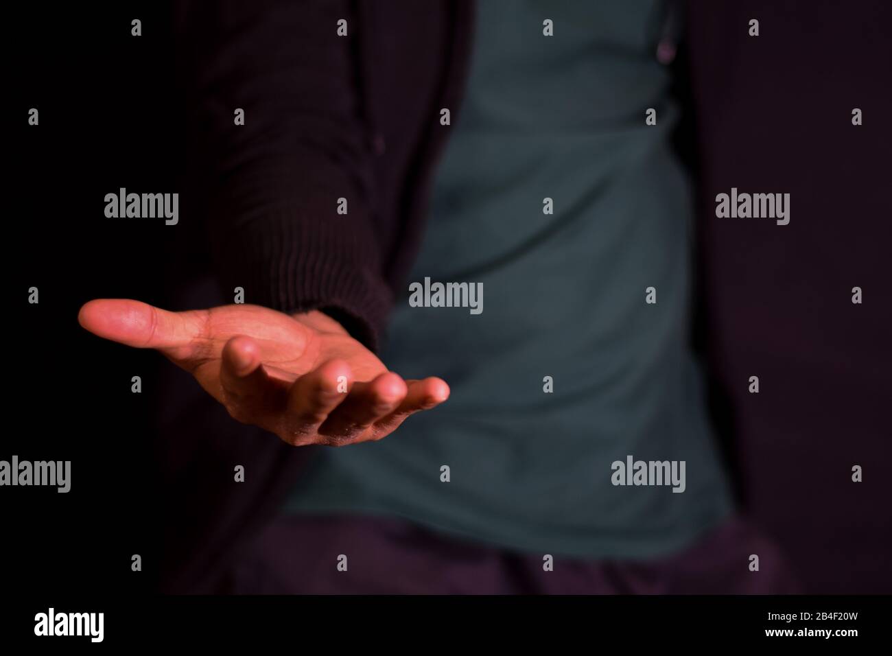 Young man showing hands it means of helping hand on dark black ...