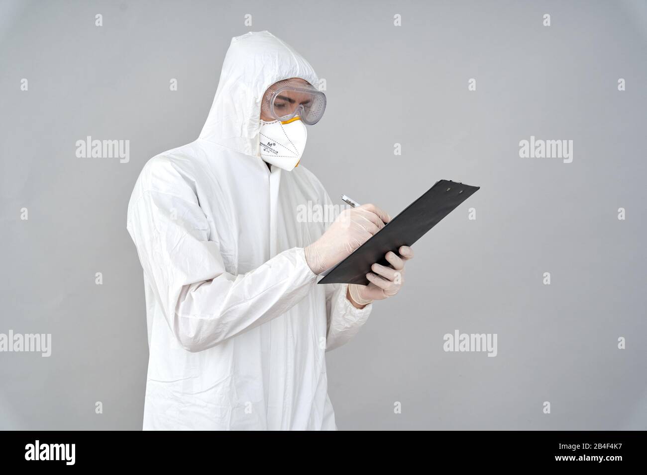 Man doctor in white hazmat suit standing isolated on gray backround ...