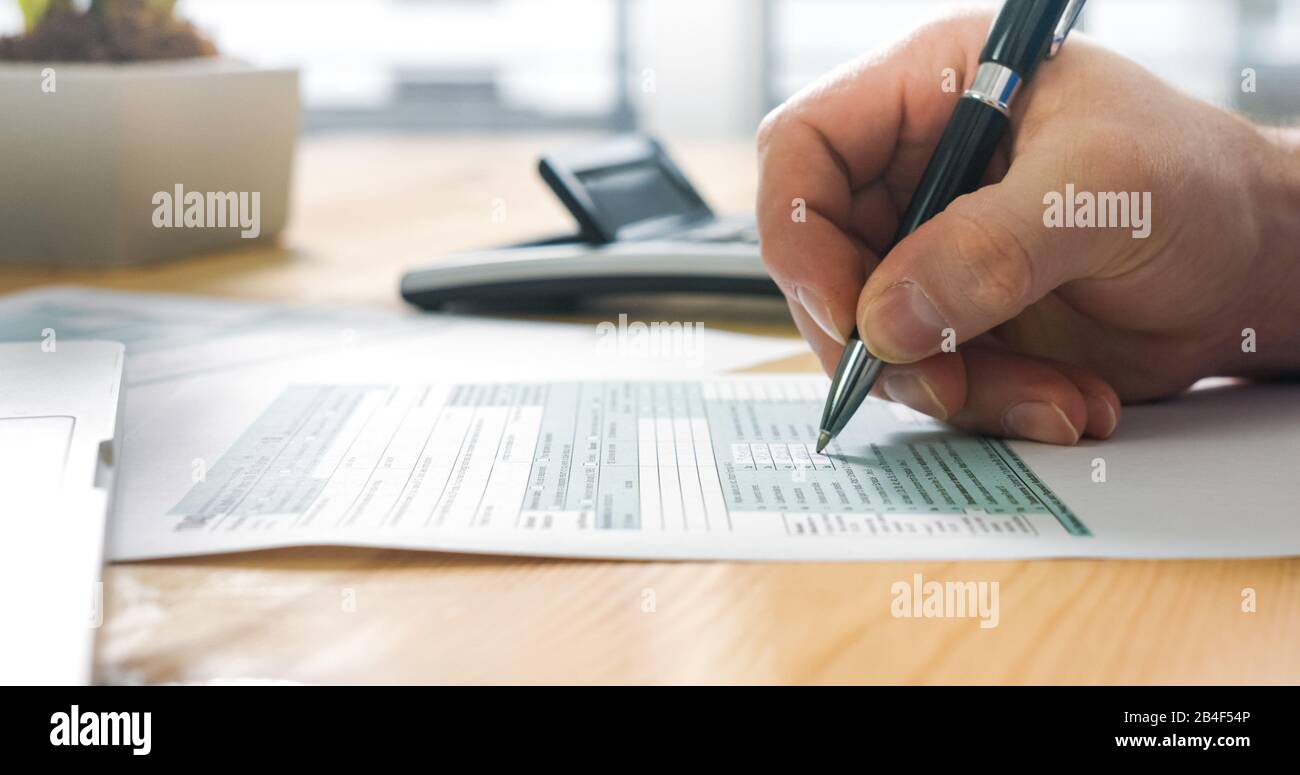 Closeup of US tax form 1040 and hand calculating and filling report ...