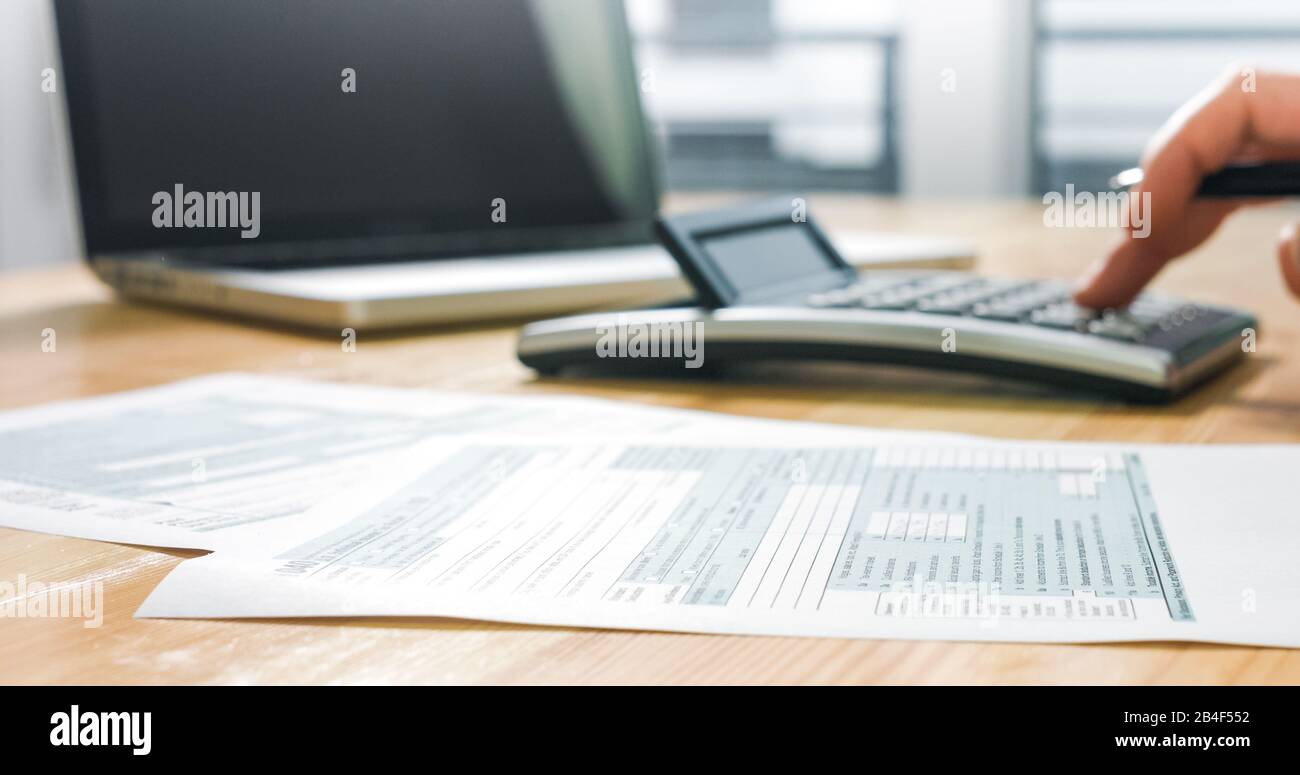 Closeup of US tax form 1040 and hand calculating and filling report ...