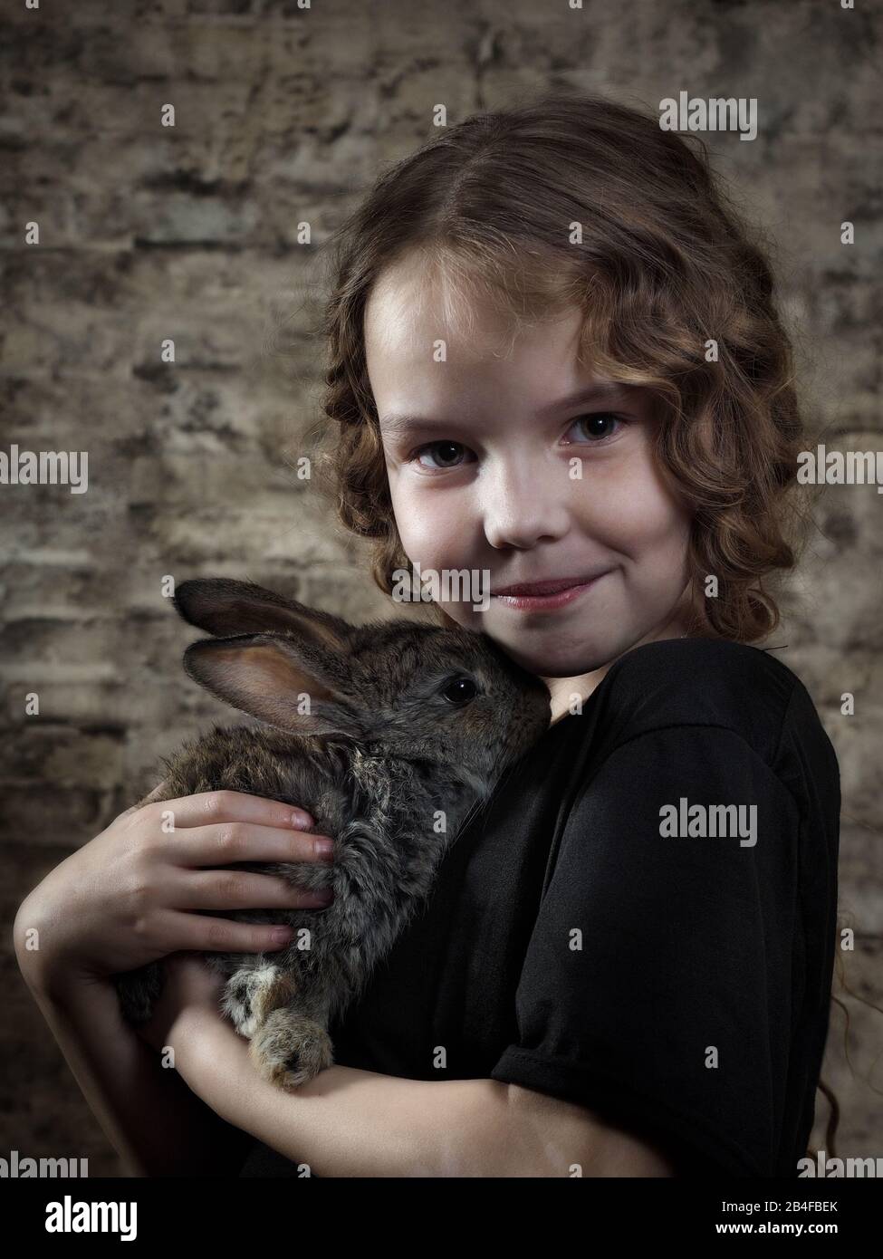 Cute girl with a rabbit in her arms. Portrait of a child with a pet ...