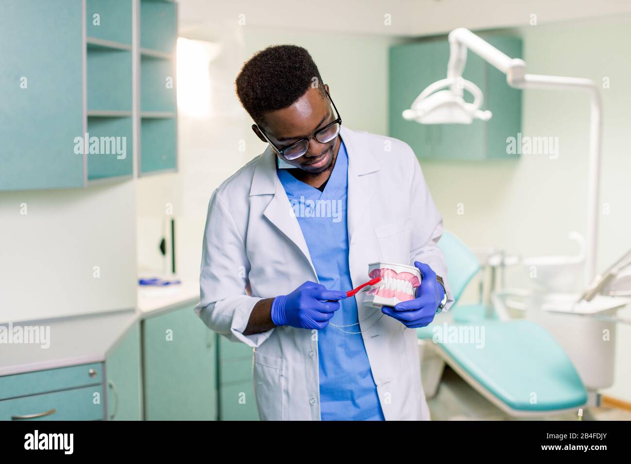 An African American dentist shows how to brush teeth with a toothbrush ...