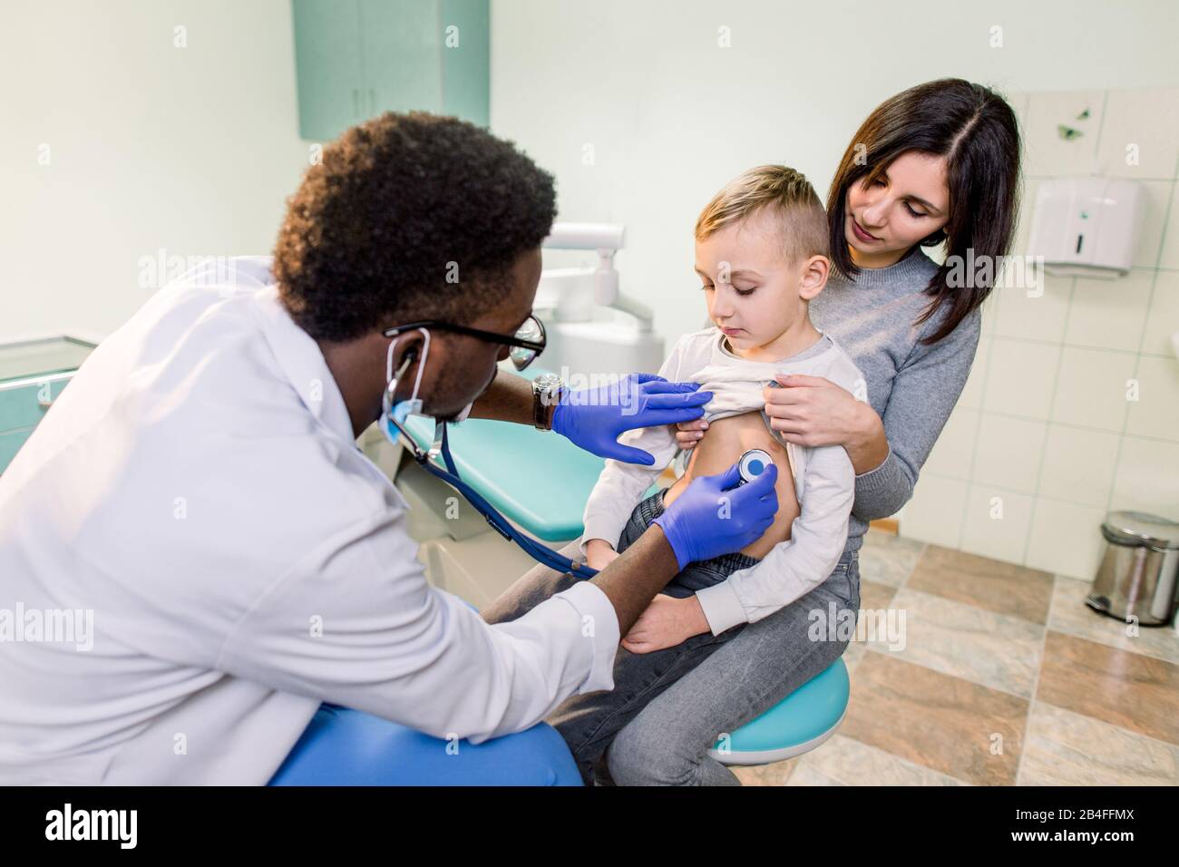 portrait of a little boy being checked by a doctor using a stethoscope ...