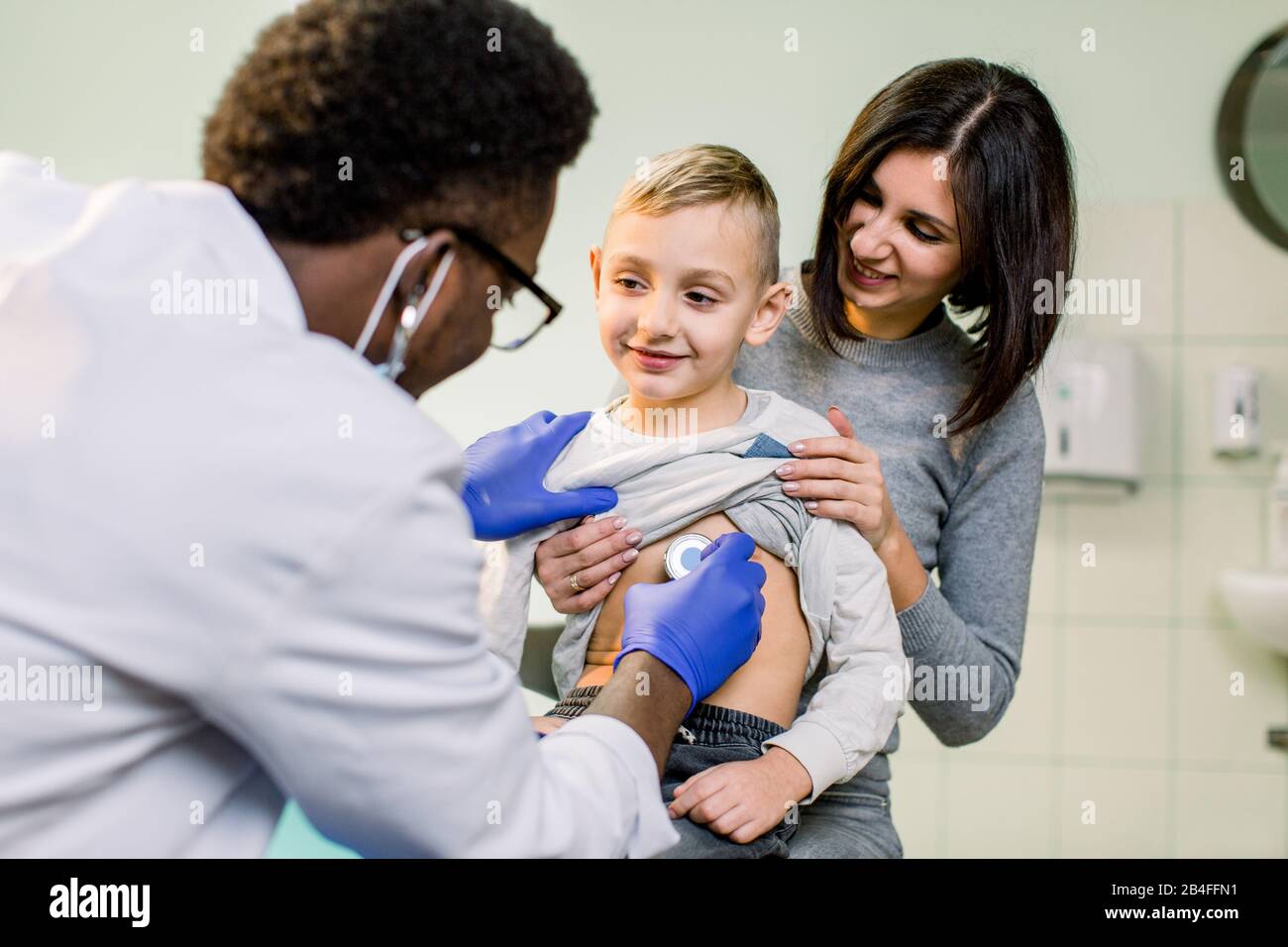 portrait of a little boy being checked by a doctor using a stethoscope ...