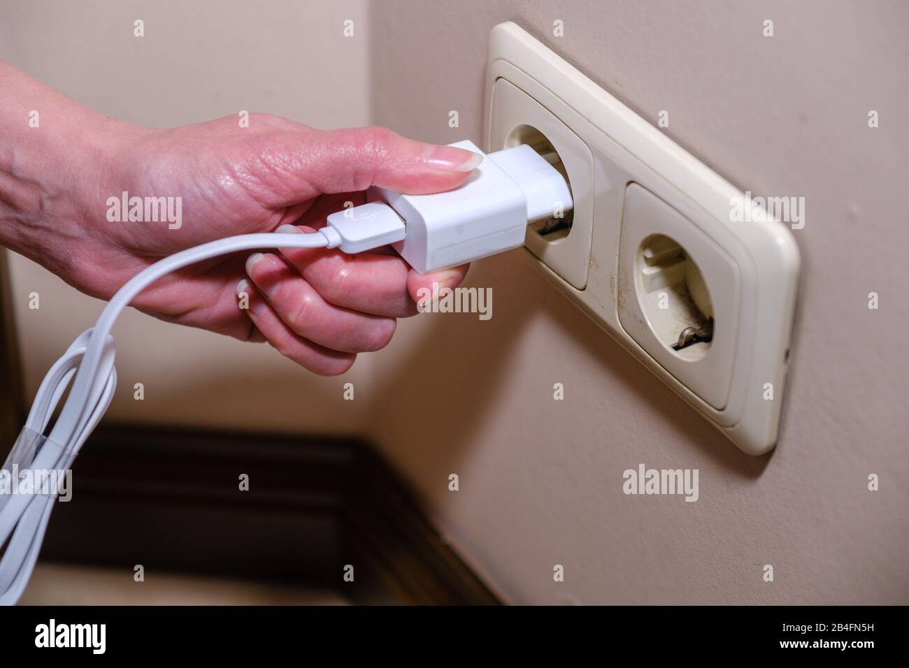 close-up woman hand puts plug in the Electricity socket. Female hand ...