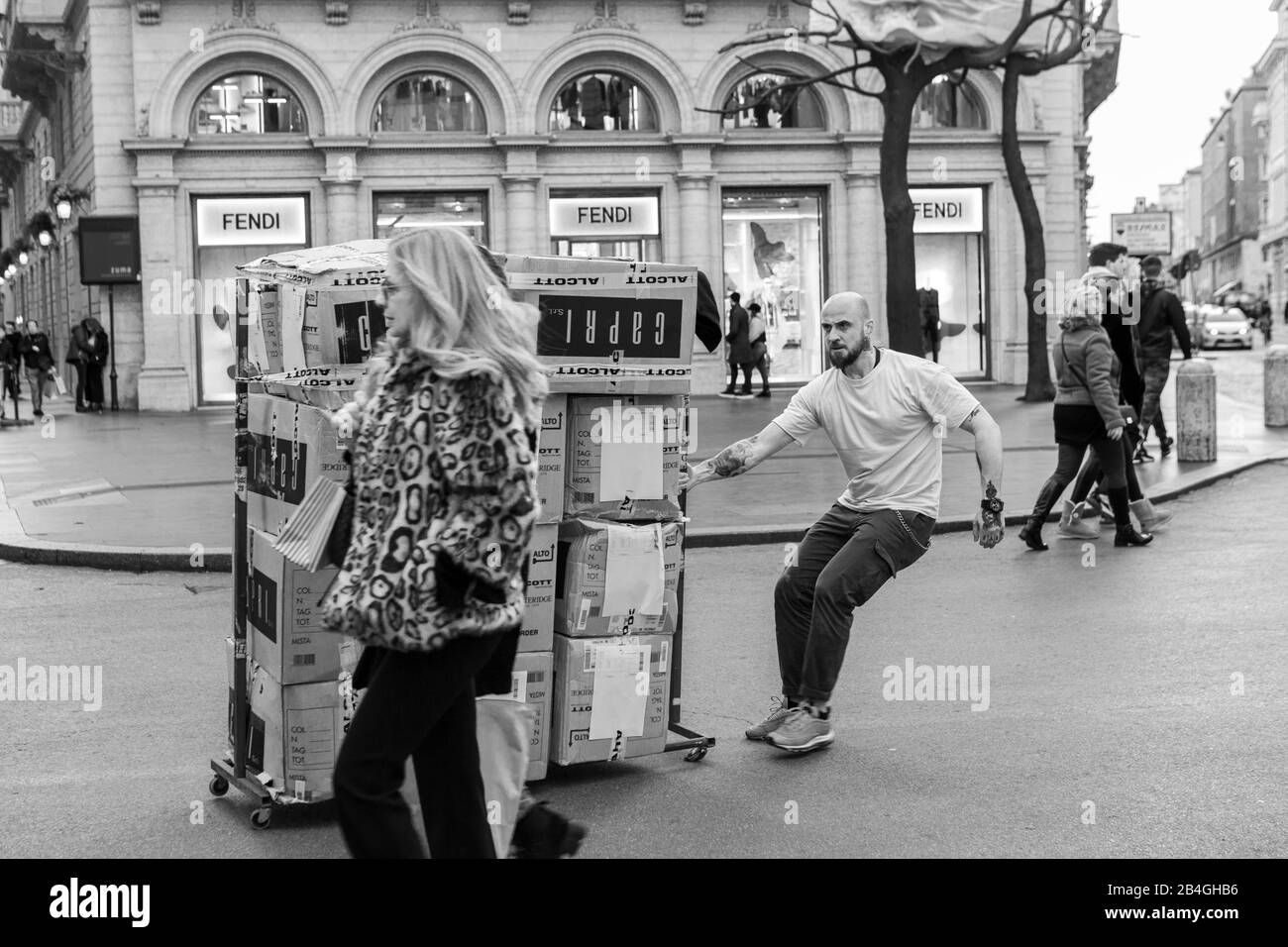 Man dragging a pallet containing boxes of clothes items in front of ...