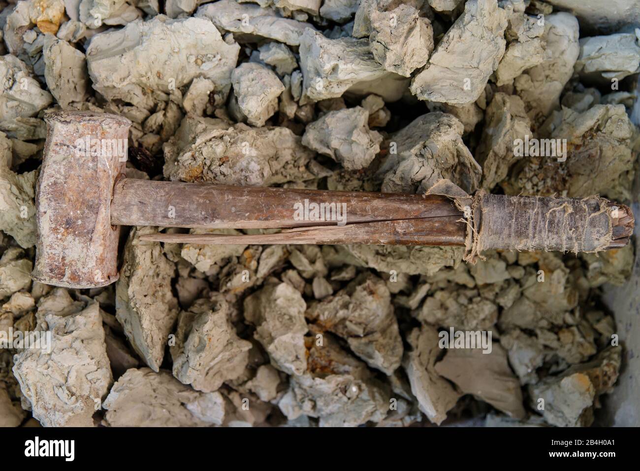 Old hammer and shattered gray dry stone clay pieces for pottery, top ...