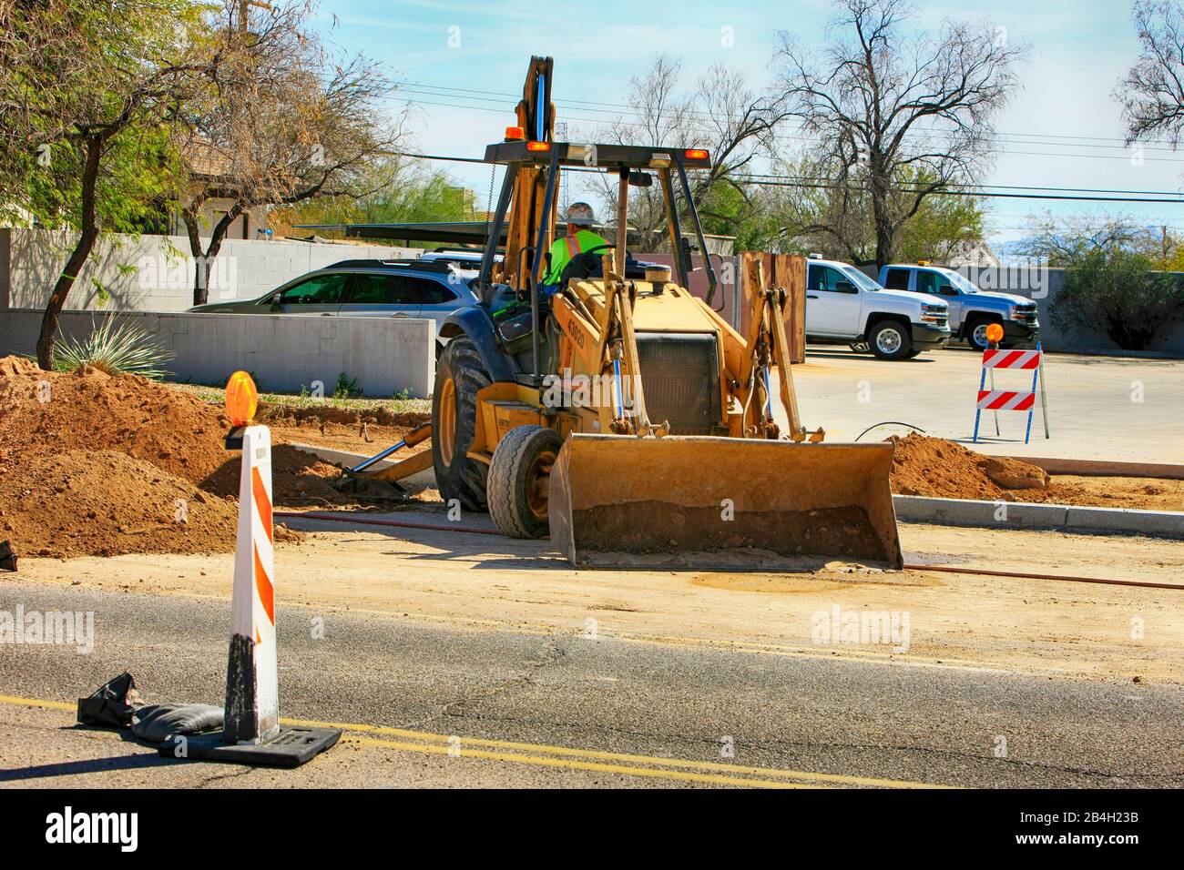 Backhoe machine digging out the sidewalk area of a road expansion ...
