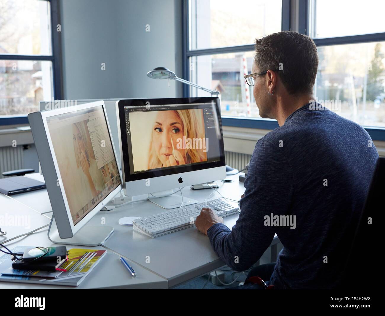Man sitting at desk in office doing image retouching hi-res stock ...