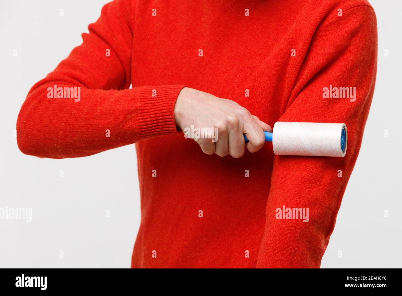 Man hand using a sticky roller to clean fabrics - red woolen knitted ...
