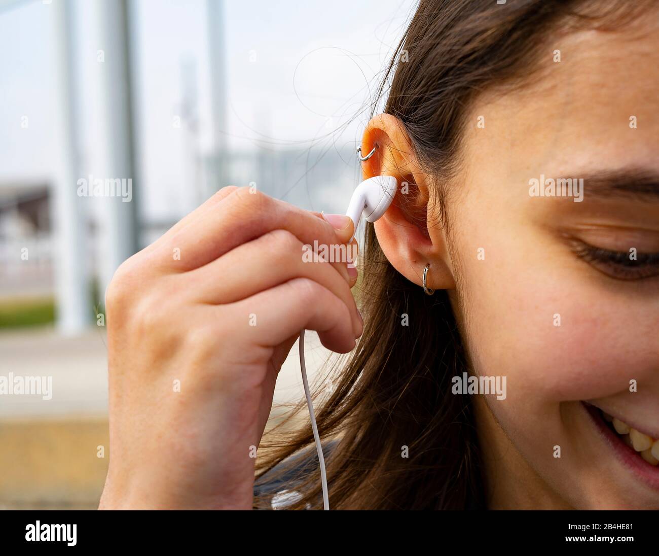 Woman putting a white headset on her ear. Headset concept Stock Photo ...
