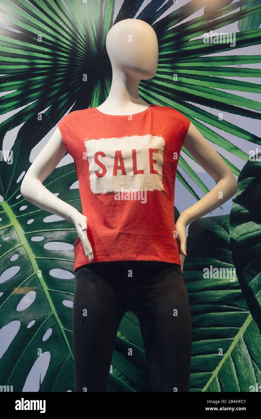 Window display with five mannequins wearing t-shirts with text sale ...