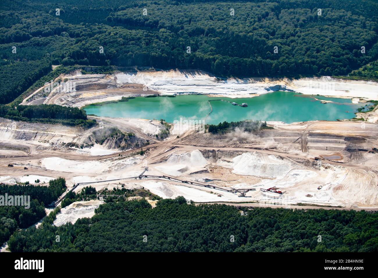 Aerial view of a quartz plant surrounded by forest with a lake, sand ...