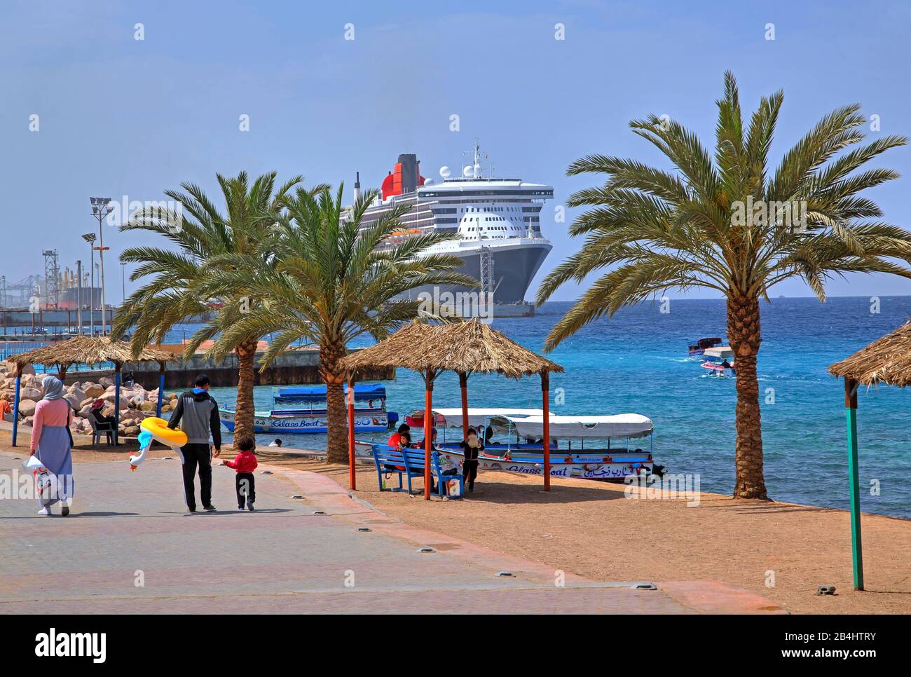 Promenade by the sea with palm trees. Excursion boats and cruise ship ...