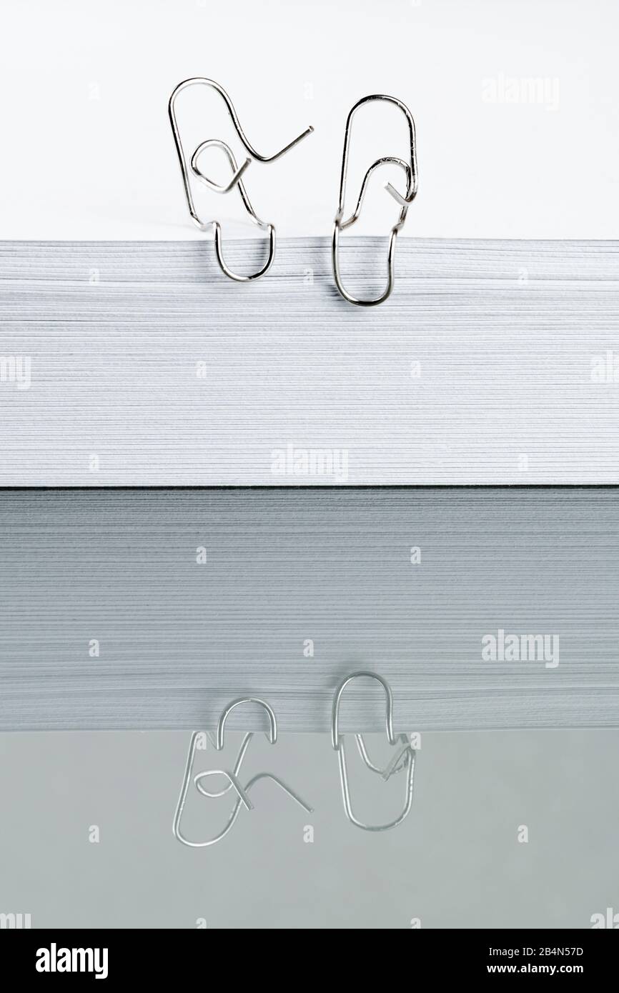 Paper clips are having a conversation, reflection Stock Photo - Alamy