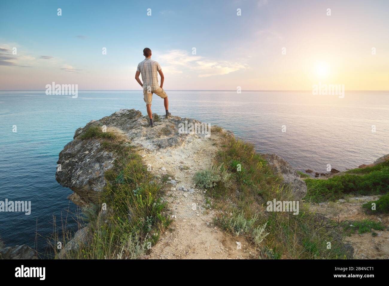 Man stands on the edge of the abyss and looks at the sea. Man relax on ...