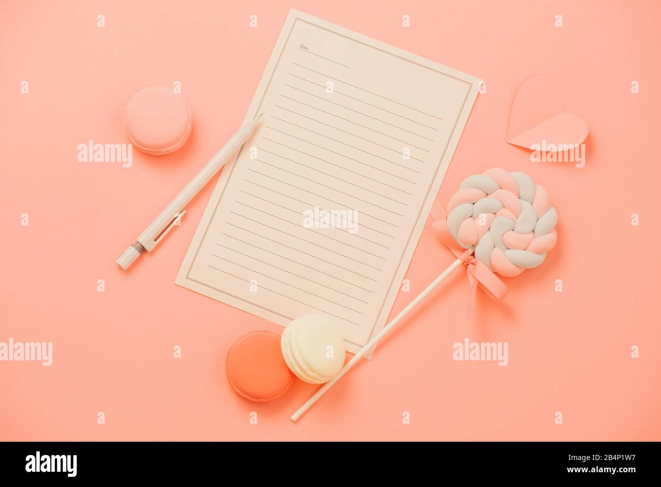 A white sheet of paper for message to loved one, macaron, candy on pink ...