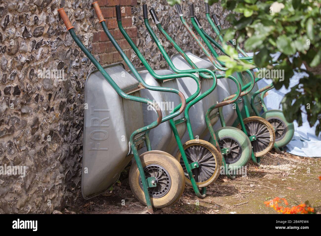 Row of wheelbarrows leant against flint wall Stock Photo - Alamy