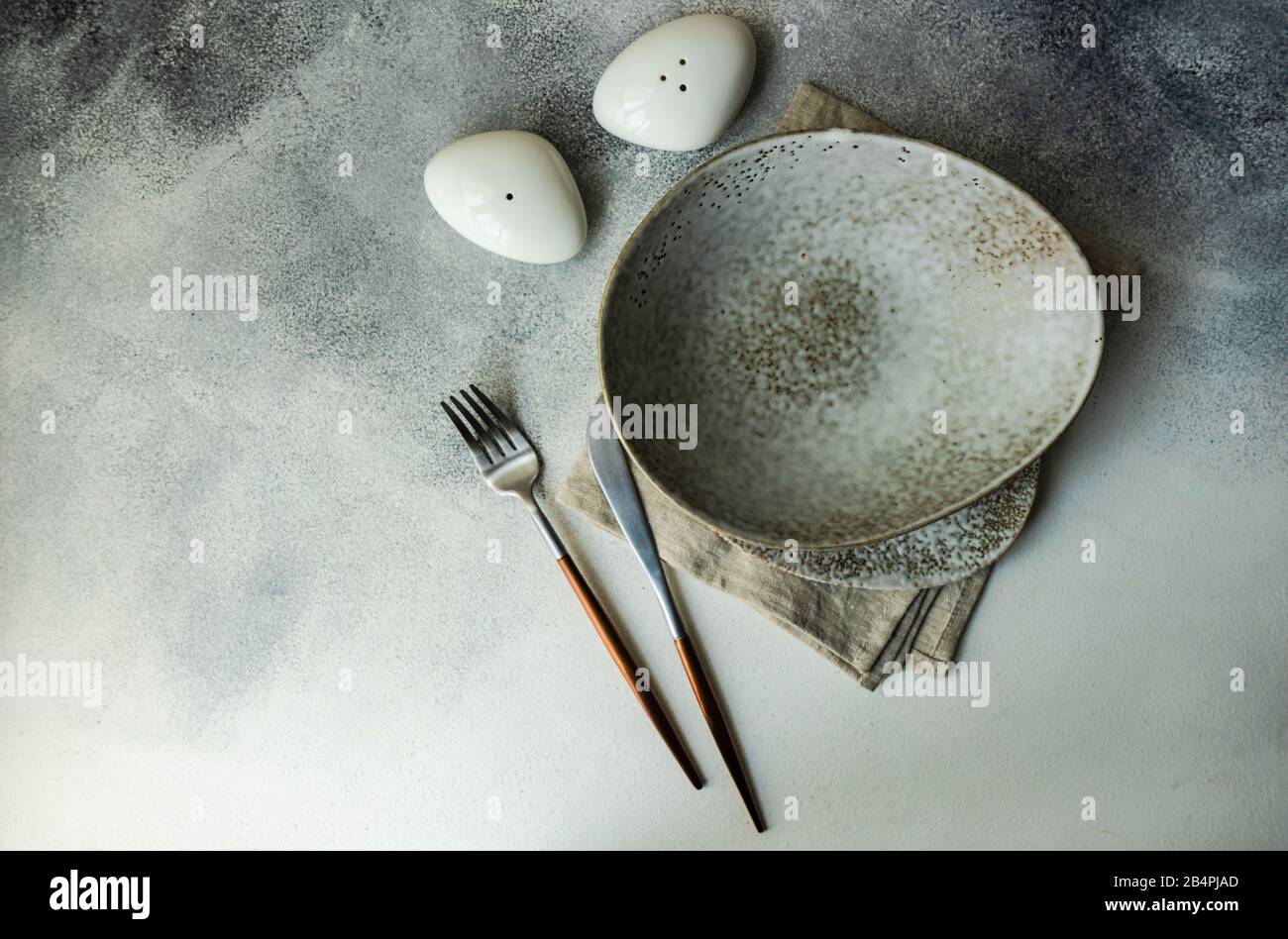 Minimalistic table setting with ceramic plates and cutlery set on stone ...