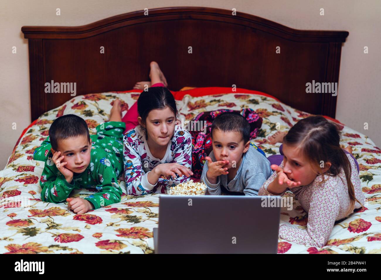 Pretty children looking at computer monitor while laying in bed and ...