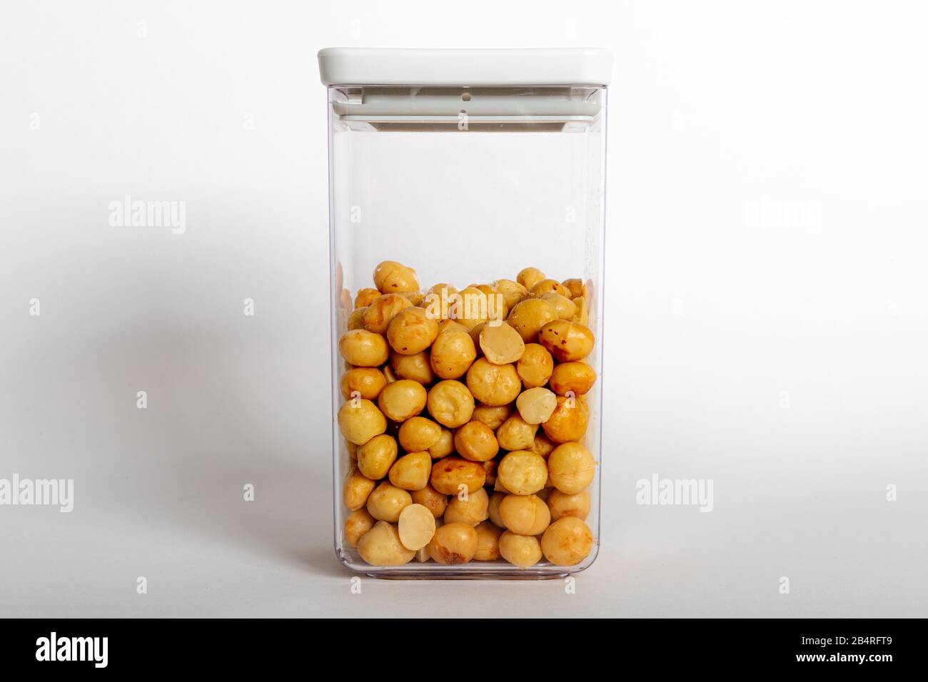 Macadamias inside a transparent plastic container with a white ...