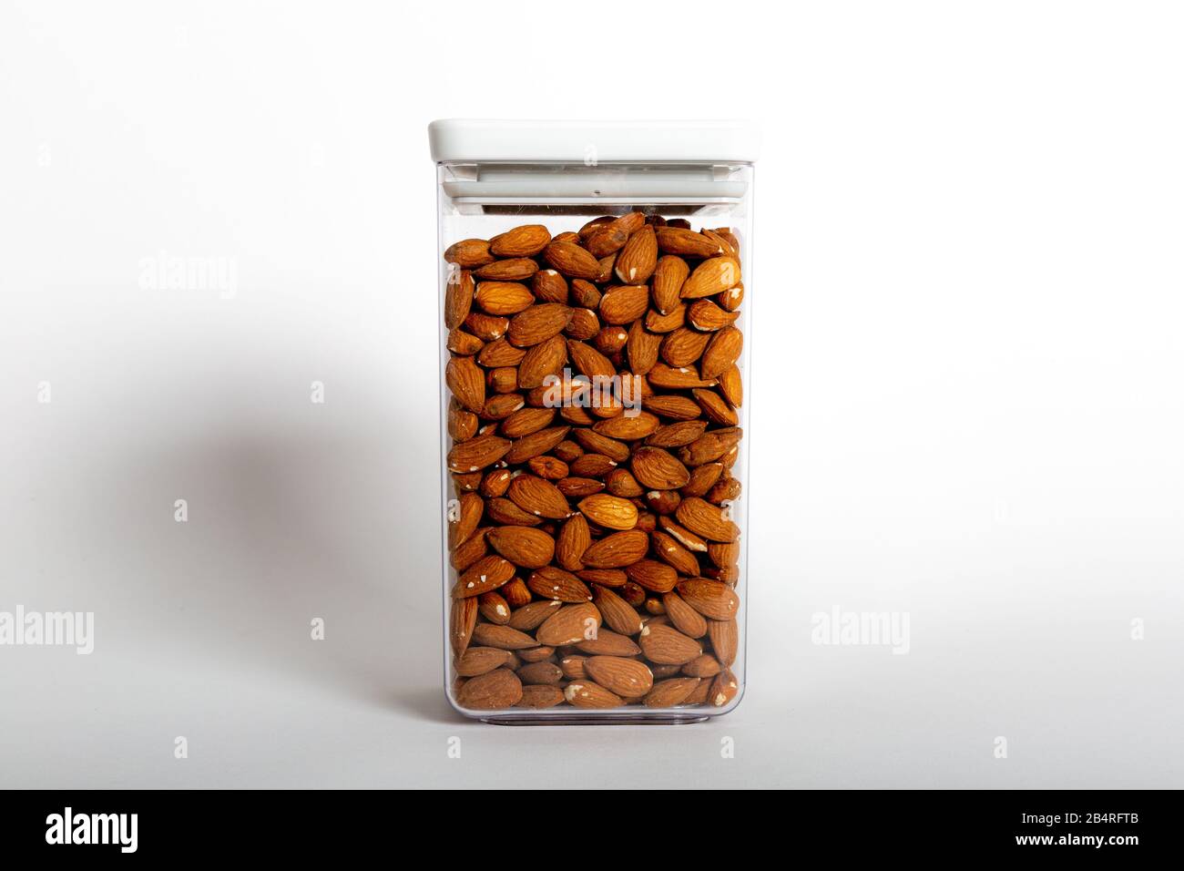 Almonds inside a transparent plastic container with a white background ...