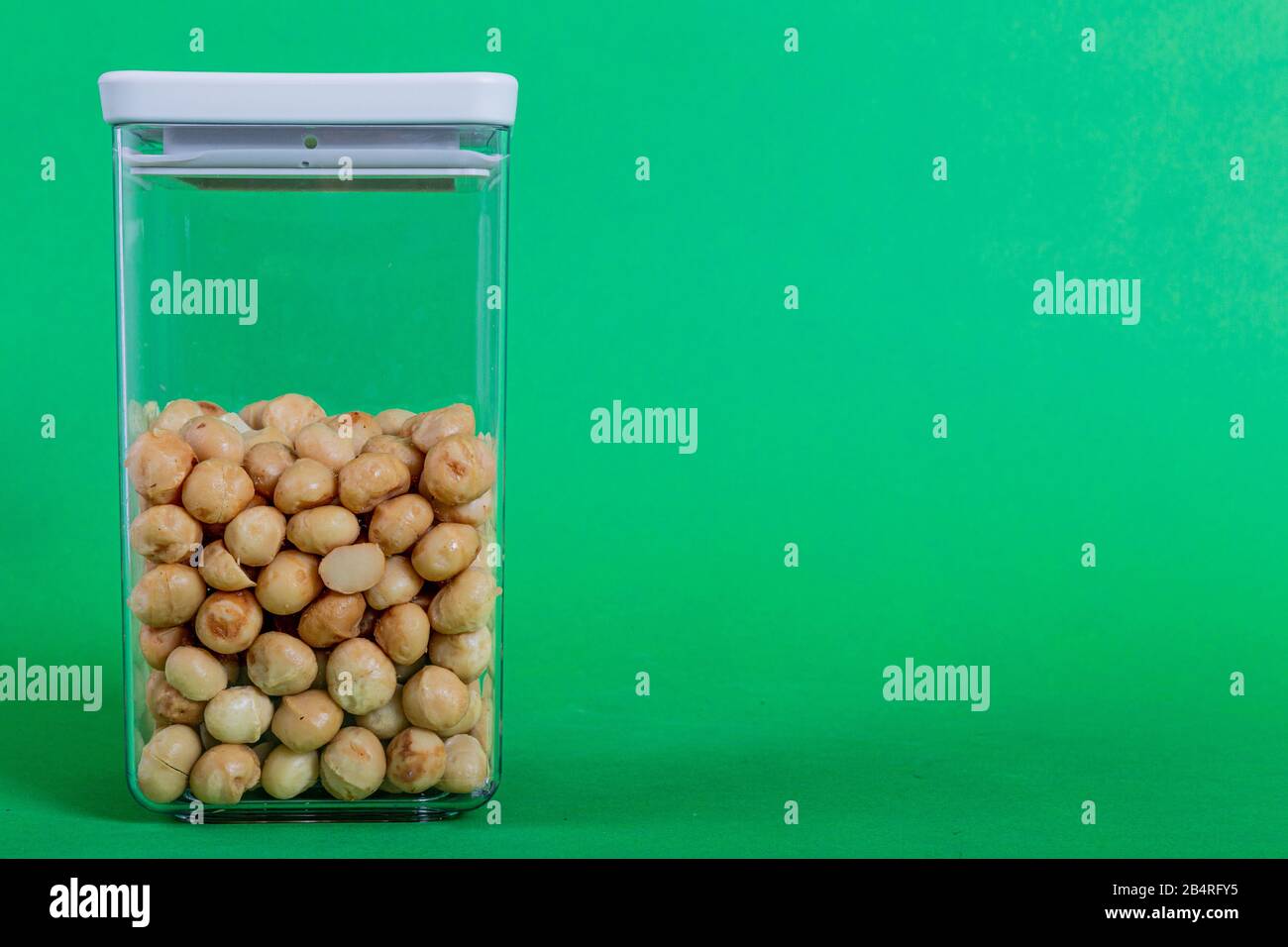 Macadamias inside a transparent plastic container with a green ...