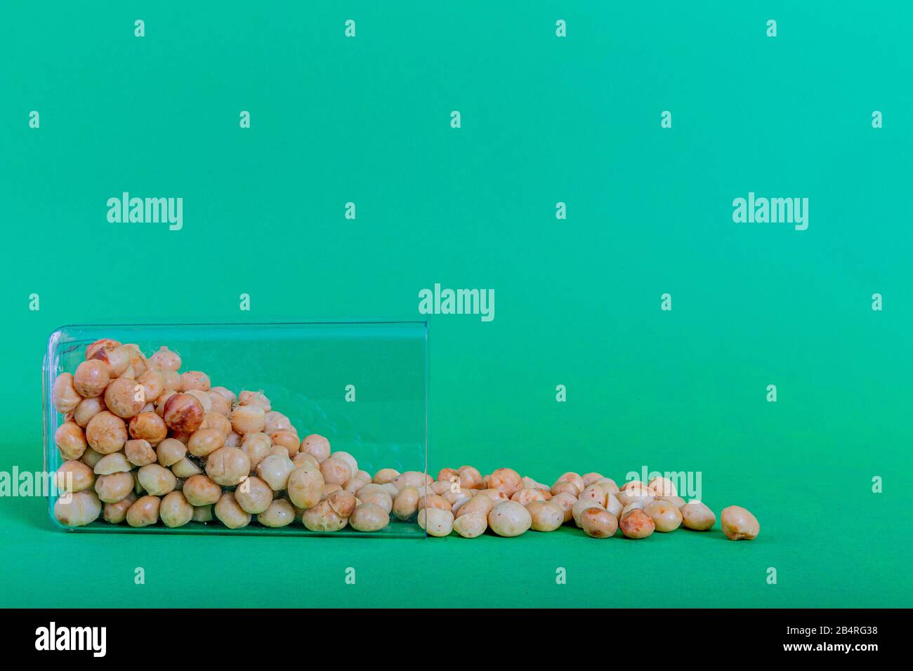 Plastic container tilted on a surface with macadamias watered with a ...