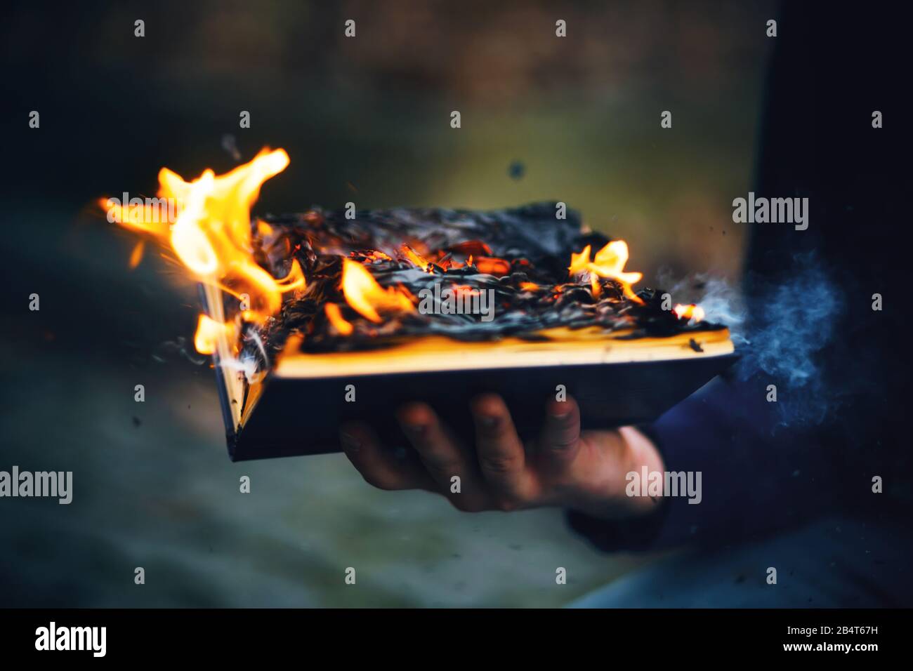 The sorcerer's hand holds a thick hardcover magic book that burns with ...