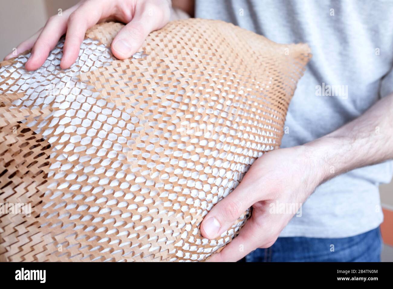Holds an object in his hand, packed in brown paper with holes. Mesh ...