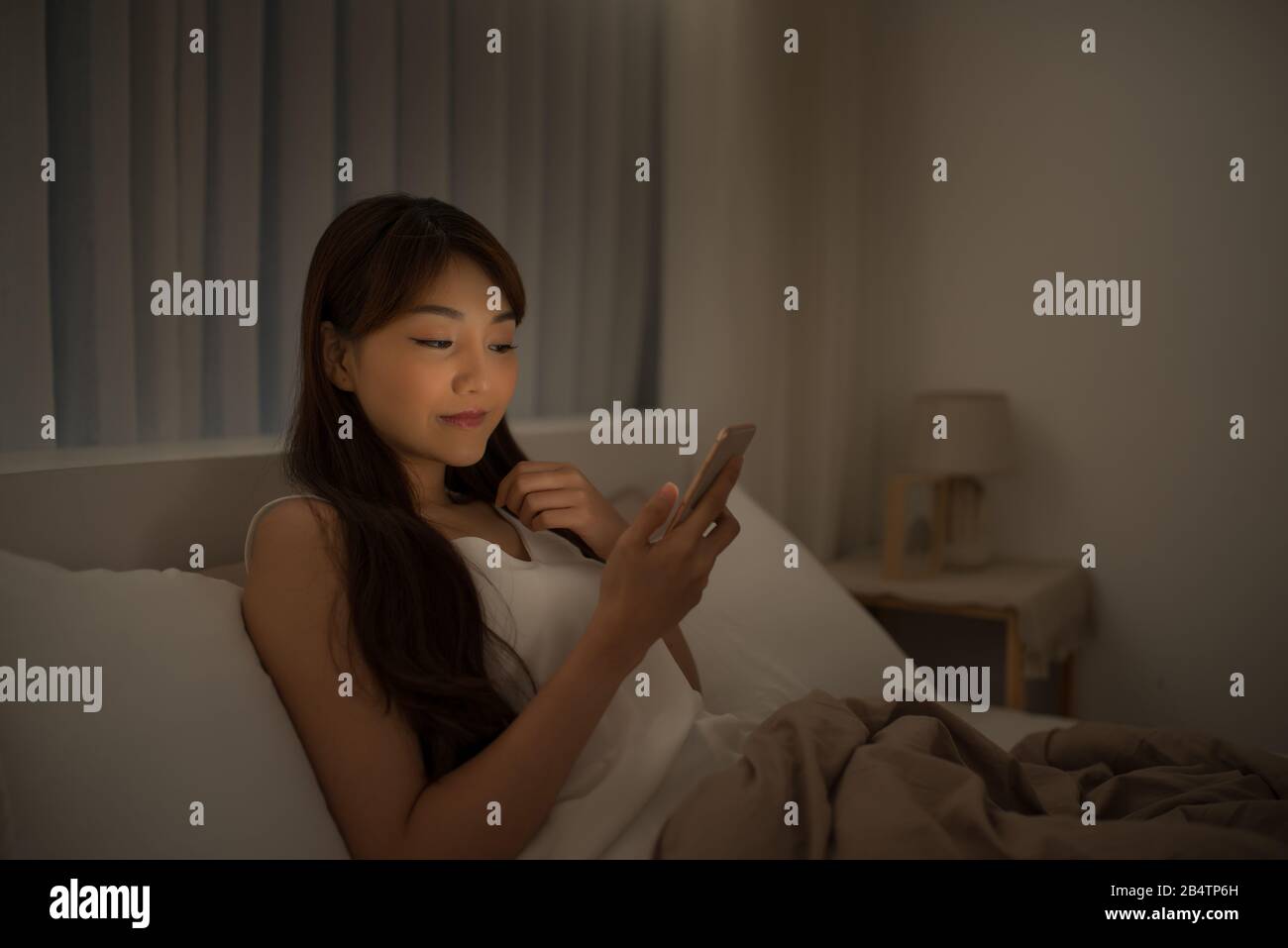 Woman use of cellphone and lying on bed at night Stock Photo - Alamy