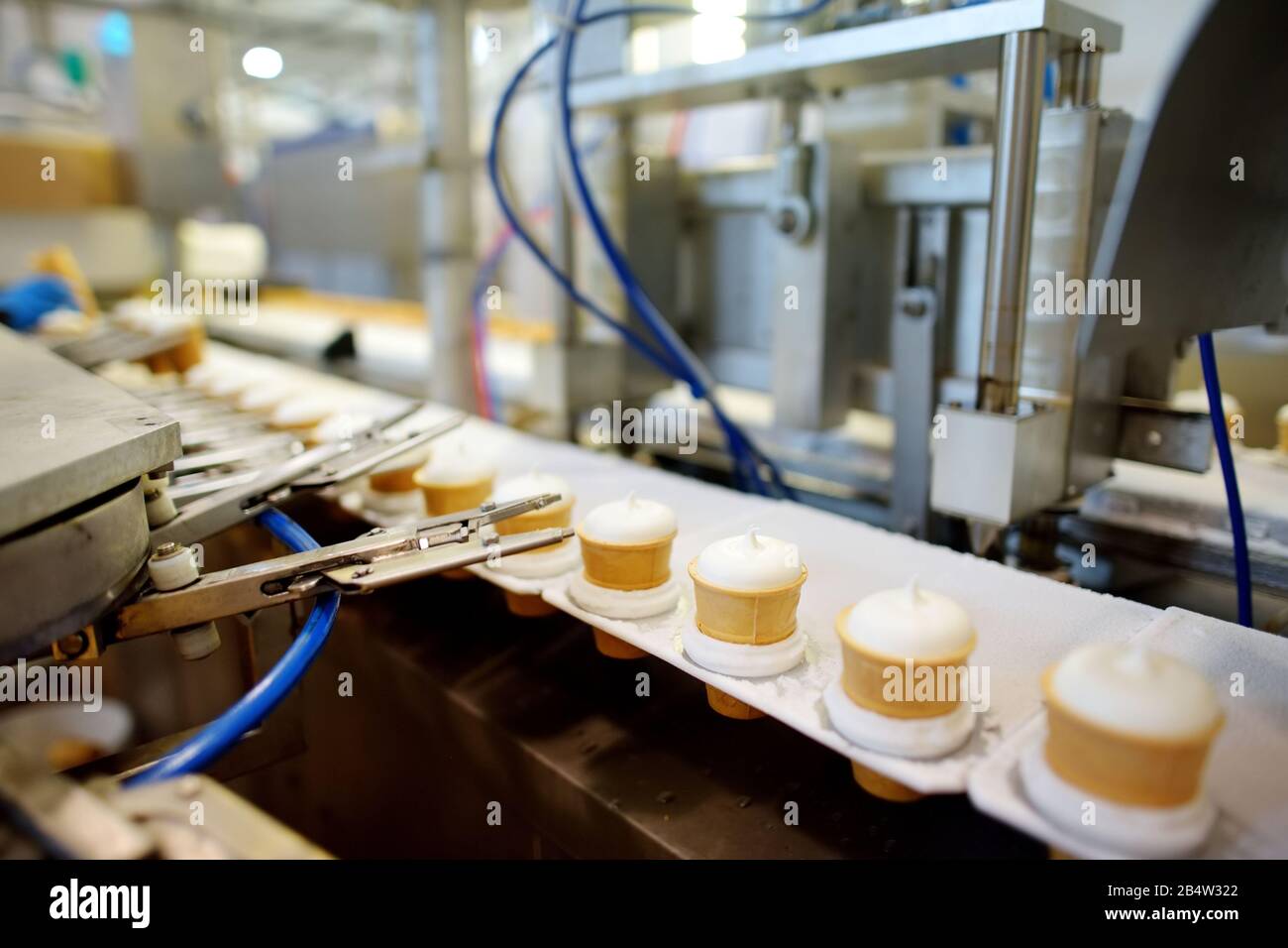 Close-up shot of moving conveyer with ice-cream cones ready for packing ...