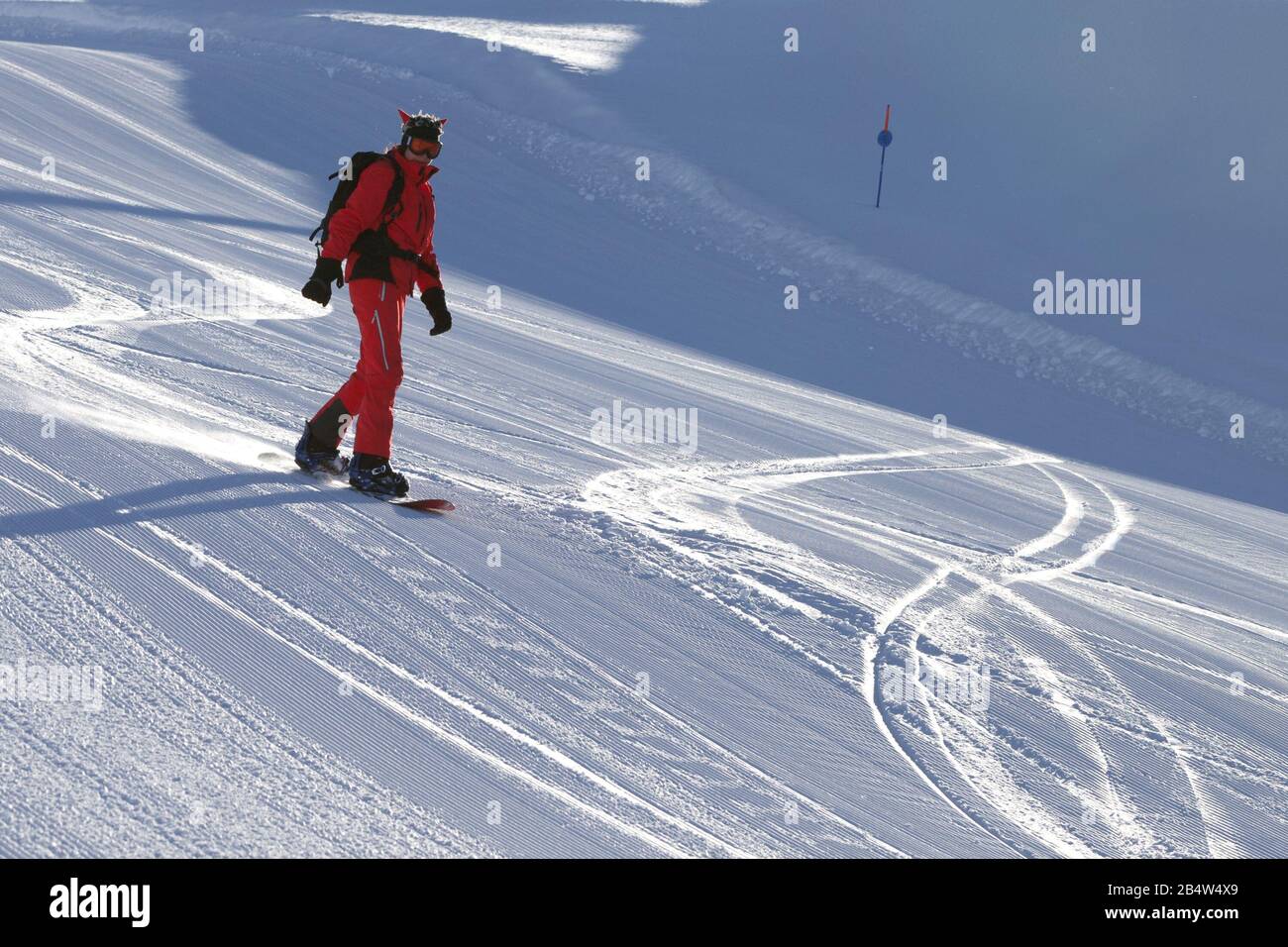 Snowboarder downhill on snowy ski slope prepared by snowcat at sunny ...