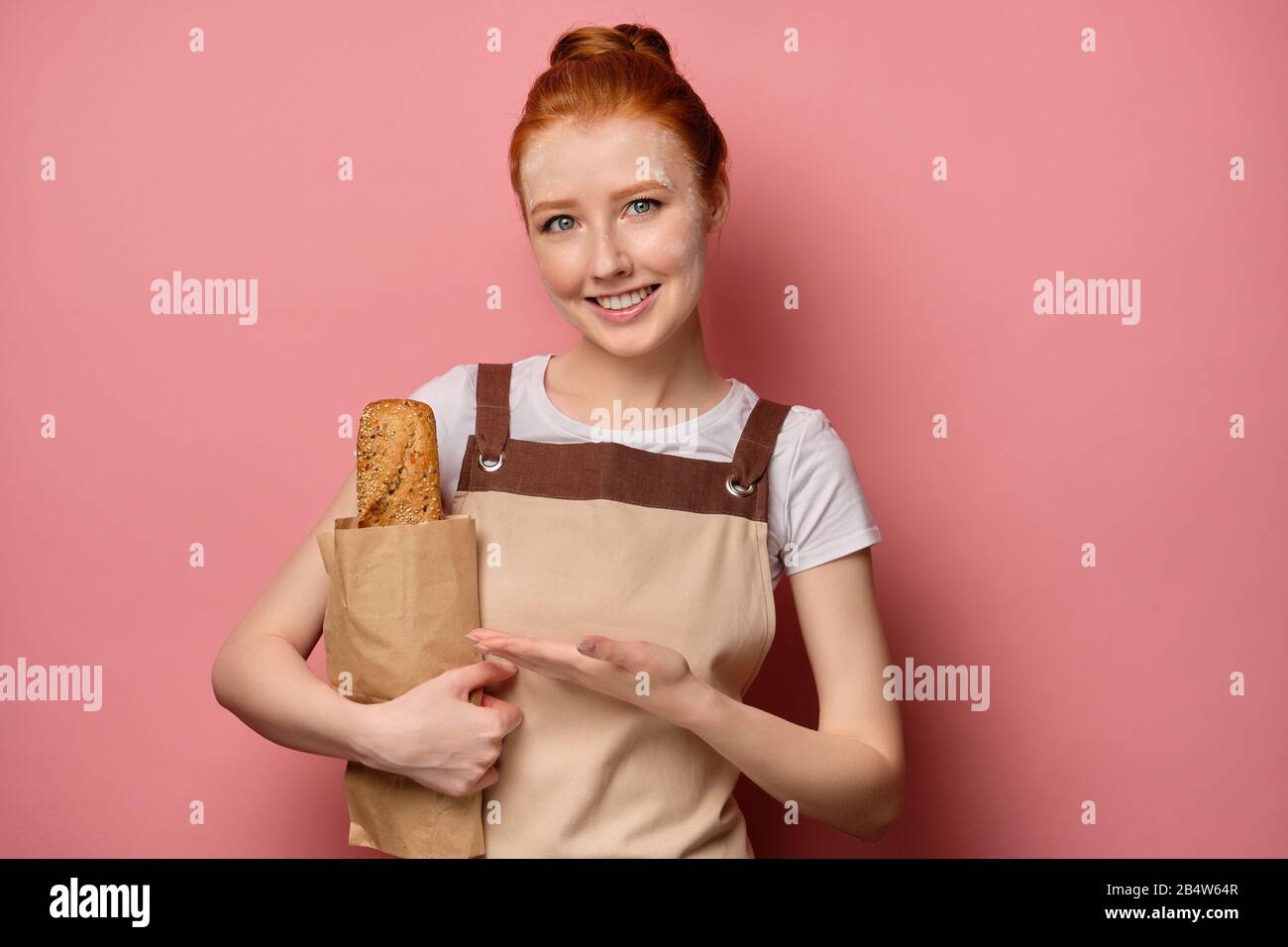 Redhead girl with gathered hair, in an apron, with flour on her face ...