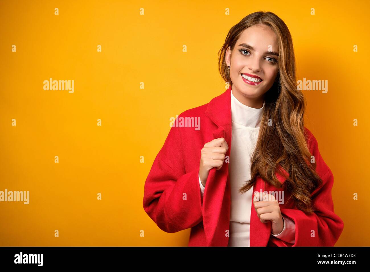 A beautiful girl with clean skin and red lipstick stands on a yellow ...