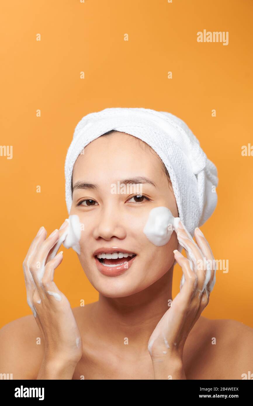 Laughing girl applying moisturizing cream on her face. Photo of young ...