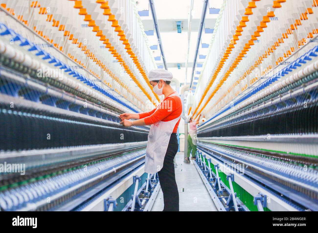 Chinese workers handle production of yarn at a textile factory in ...