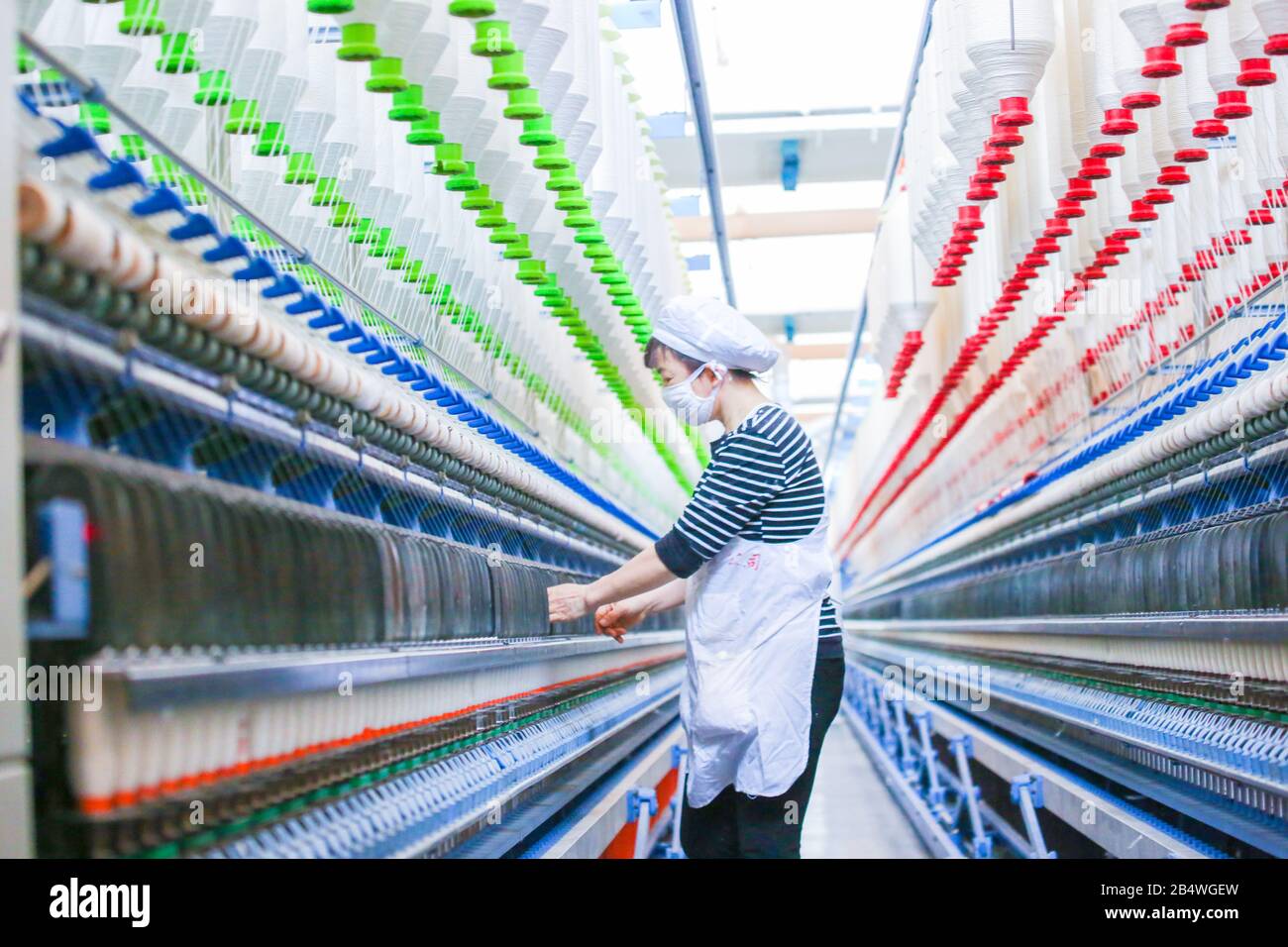 A Chinese worker handles production of yarn at a textile factory in ...