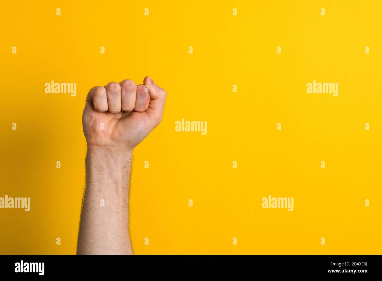 close up man hand fist over a yellow background. winner and power sign ...