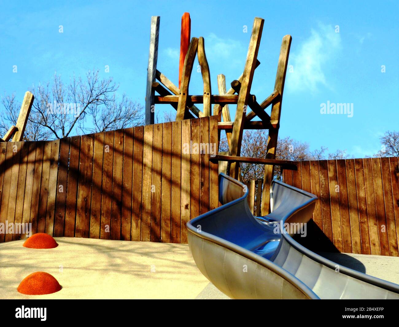 stainless steel slide in playground. public park setting on hill side ...