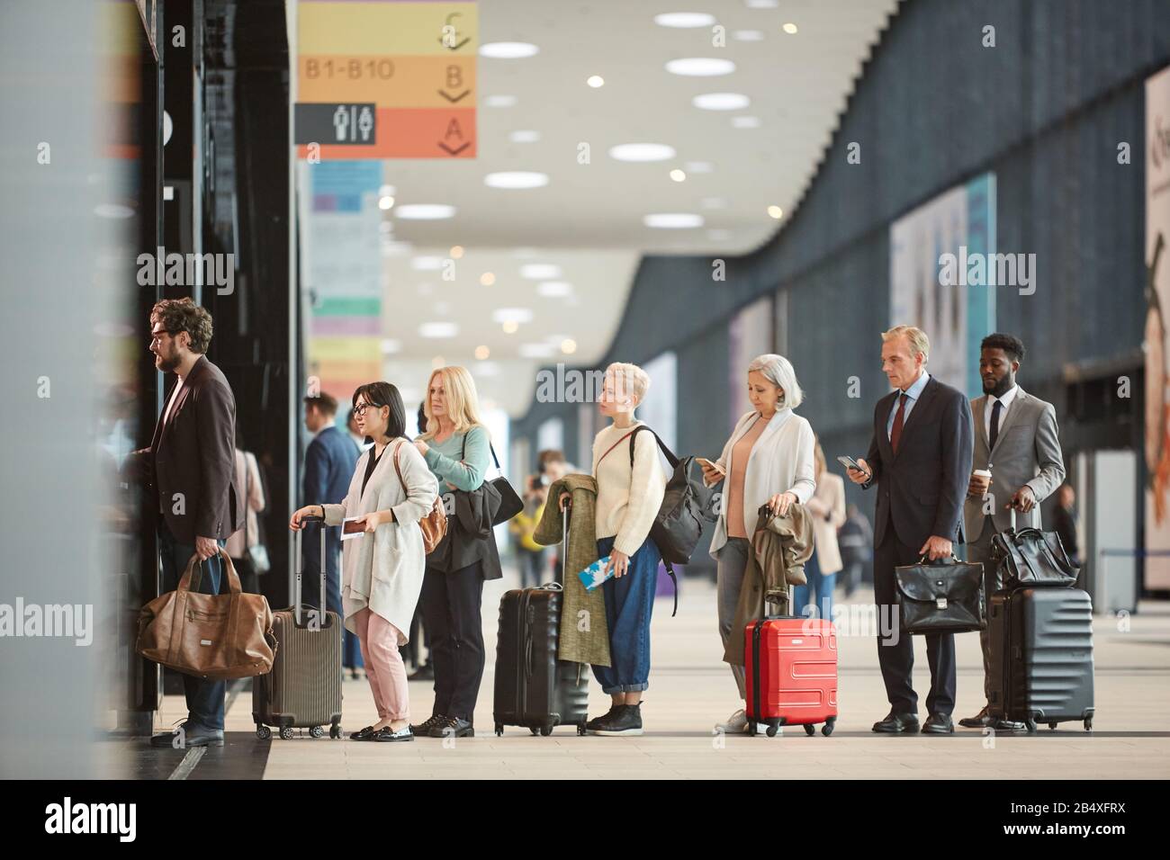 Horizontal side view shot of people standing in queue with their ...