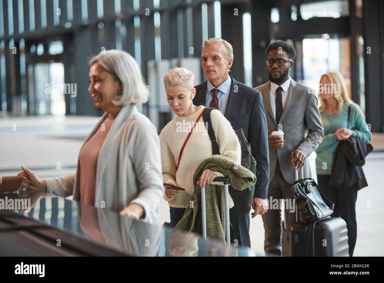 Group of people standing in queue at airport check-in counter desk ...