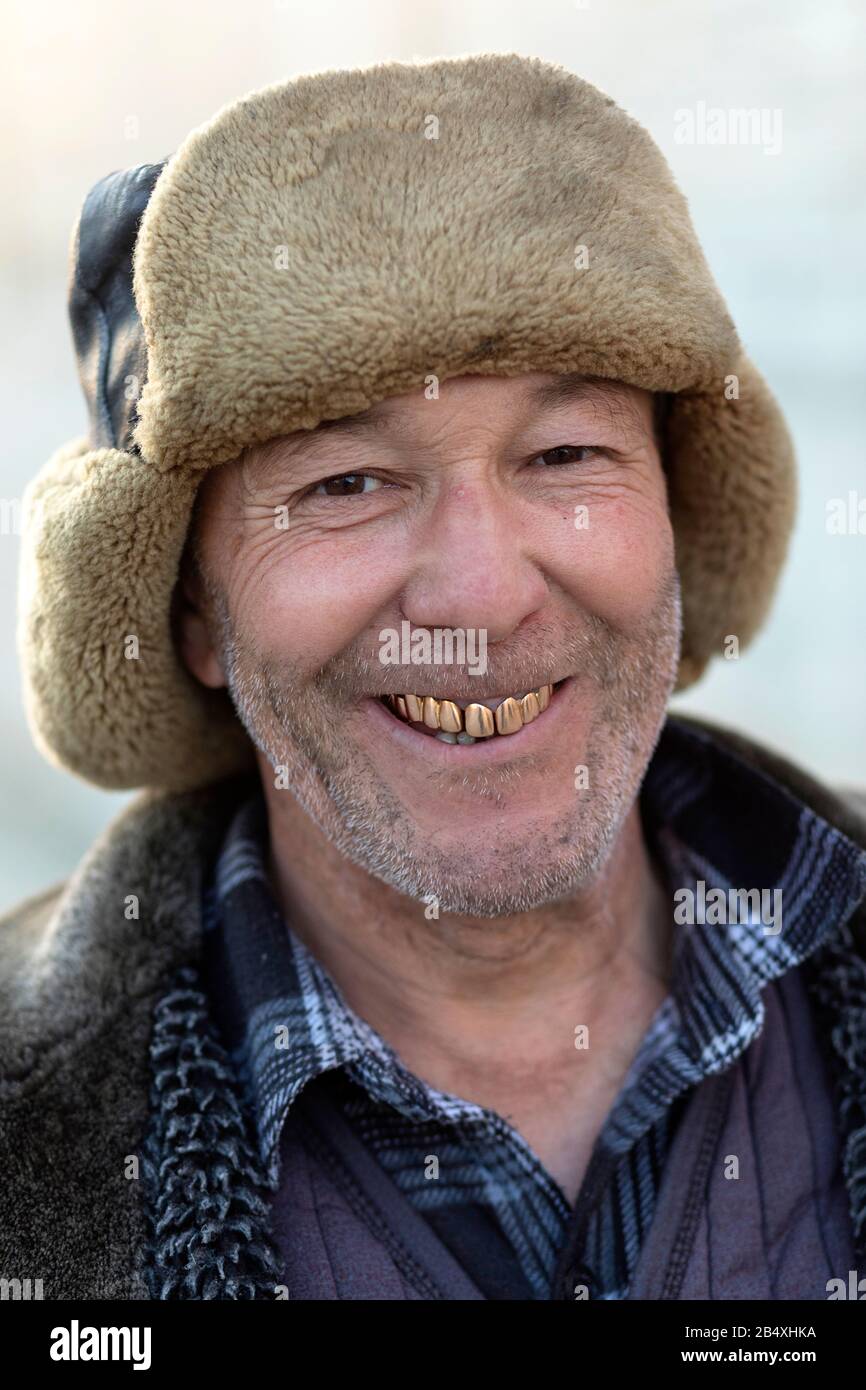 Portrait of friendly Uzbek salesman with fur hat and golden teeth ...