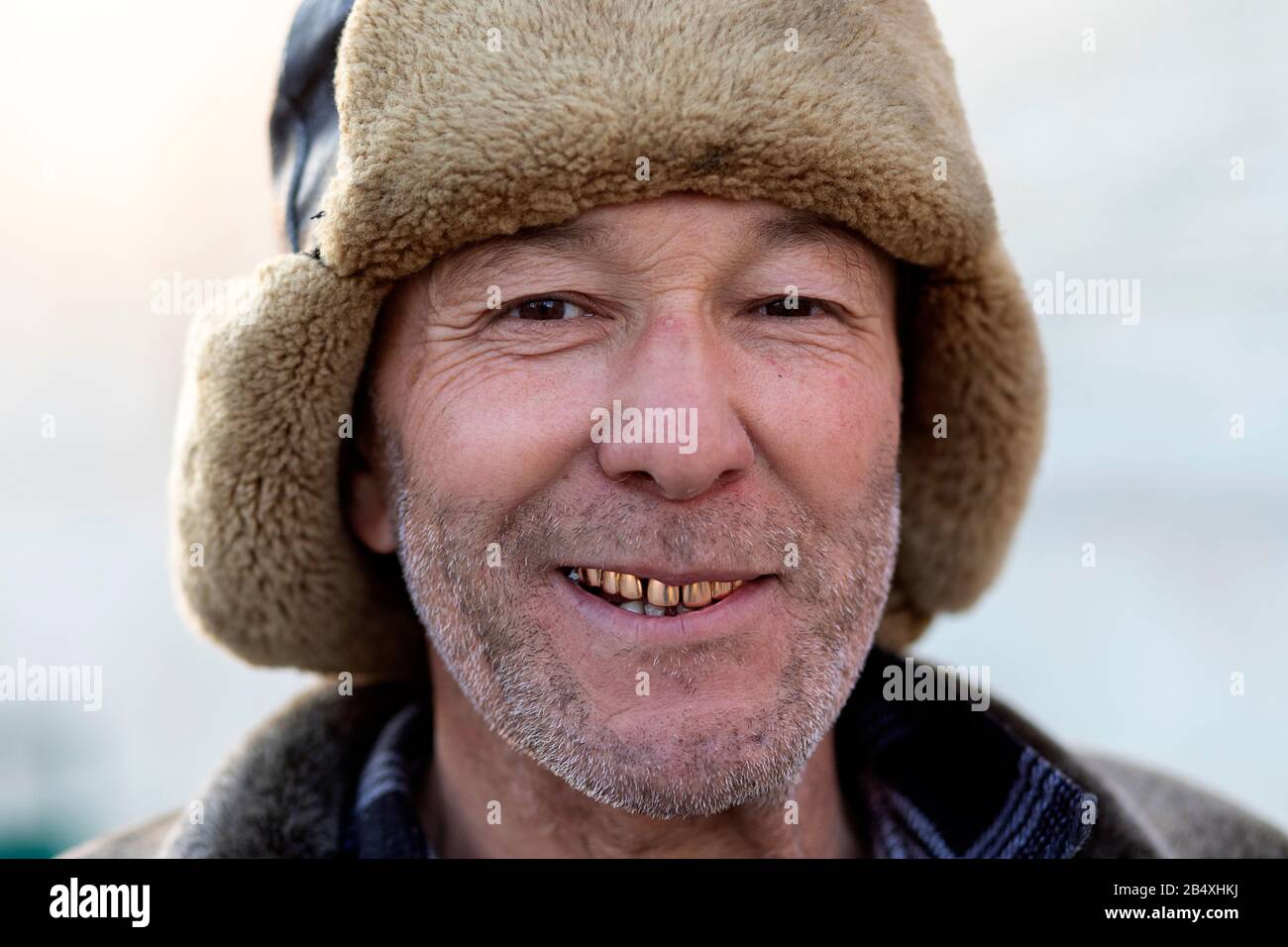 Portrait of friendly Uzbek salesman with fur hat and golden teeth ...